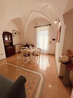 Uma área de refeições com mesa e cadeiras, uma cozinha com armários e uma janela com cortinas.
