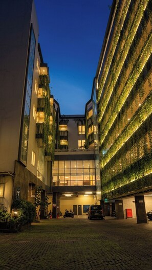 Um edifício moderno com vários andares, grandes janelas e um pátio pavimentado.
