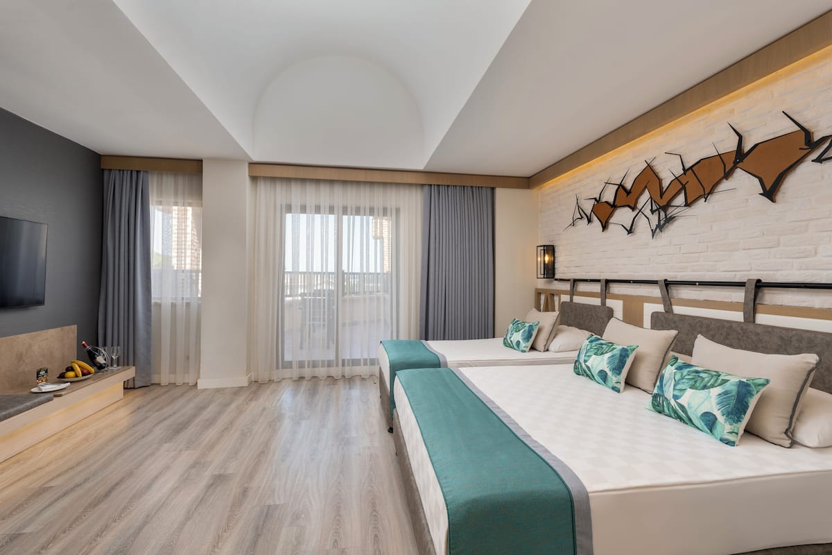 Quarto de hotel moderno com duas camas, televisão de tela plana, um banco de madeira e um objeto decorativo na parede.