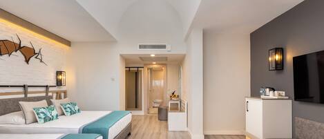 Quarto de hotel moderno com duas camas, um sofá, uma TV e uma pequena cozinha.