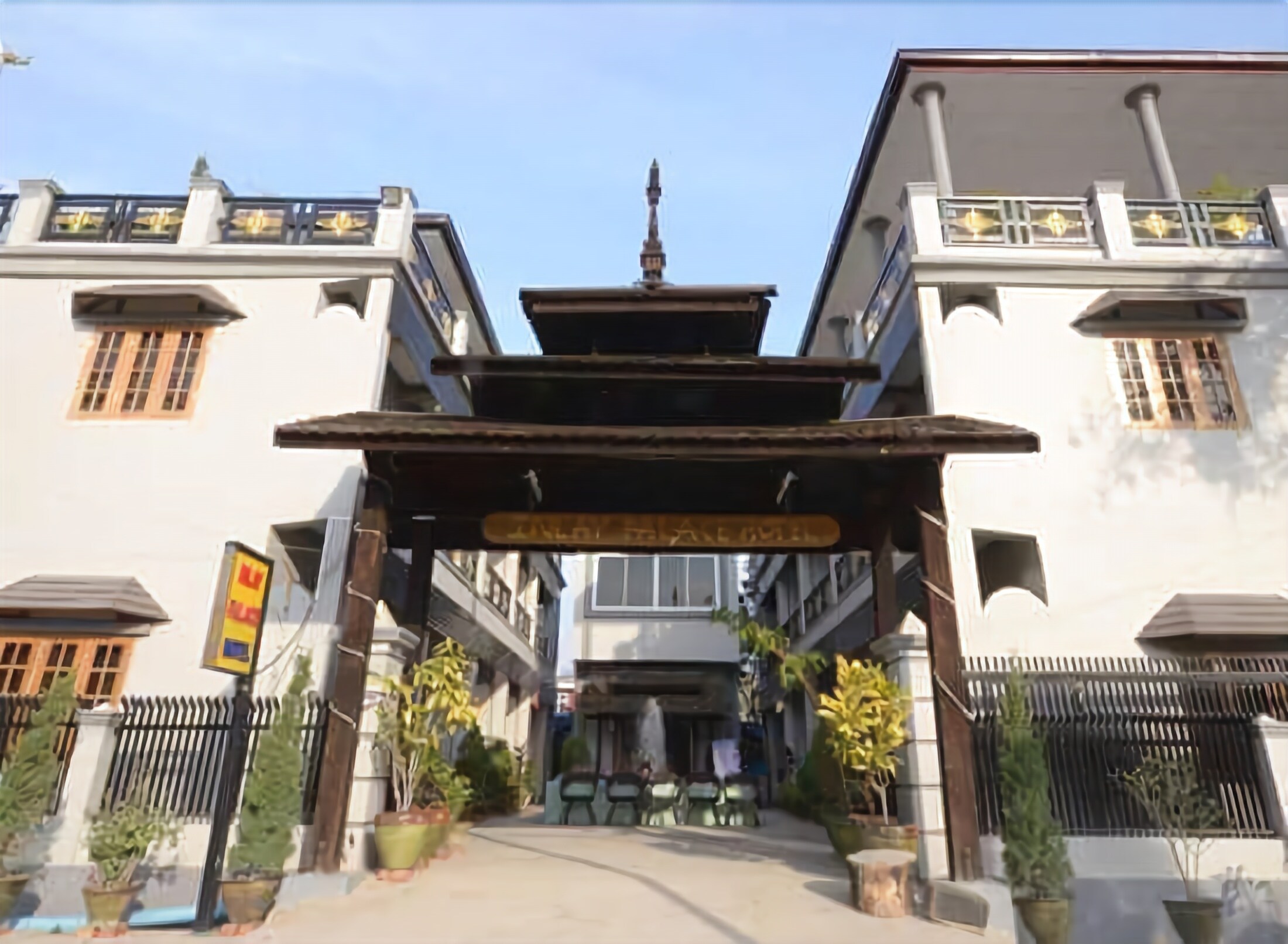 Um edifício tradicional com entrada central, plantas em vasos e uma placa.
