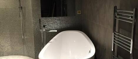 Um banheiro moderno com uma banheira de pé, chuveiro sem barreiras e um porta-toalhas.