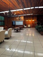 Um quarto espaçoso com teto de madeira, um candelabro e uma área de jantar com mesa e cadeiras.
