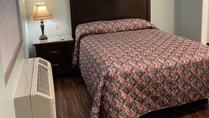 Quarto com cama, mesa de cabeceira, abajur e ar condicionado.