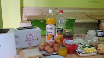 Mesa de café da manhã com torradas, ovos, suco de laranja e diversos acompanhamentos.