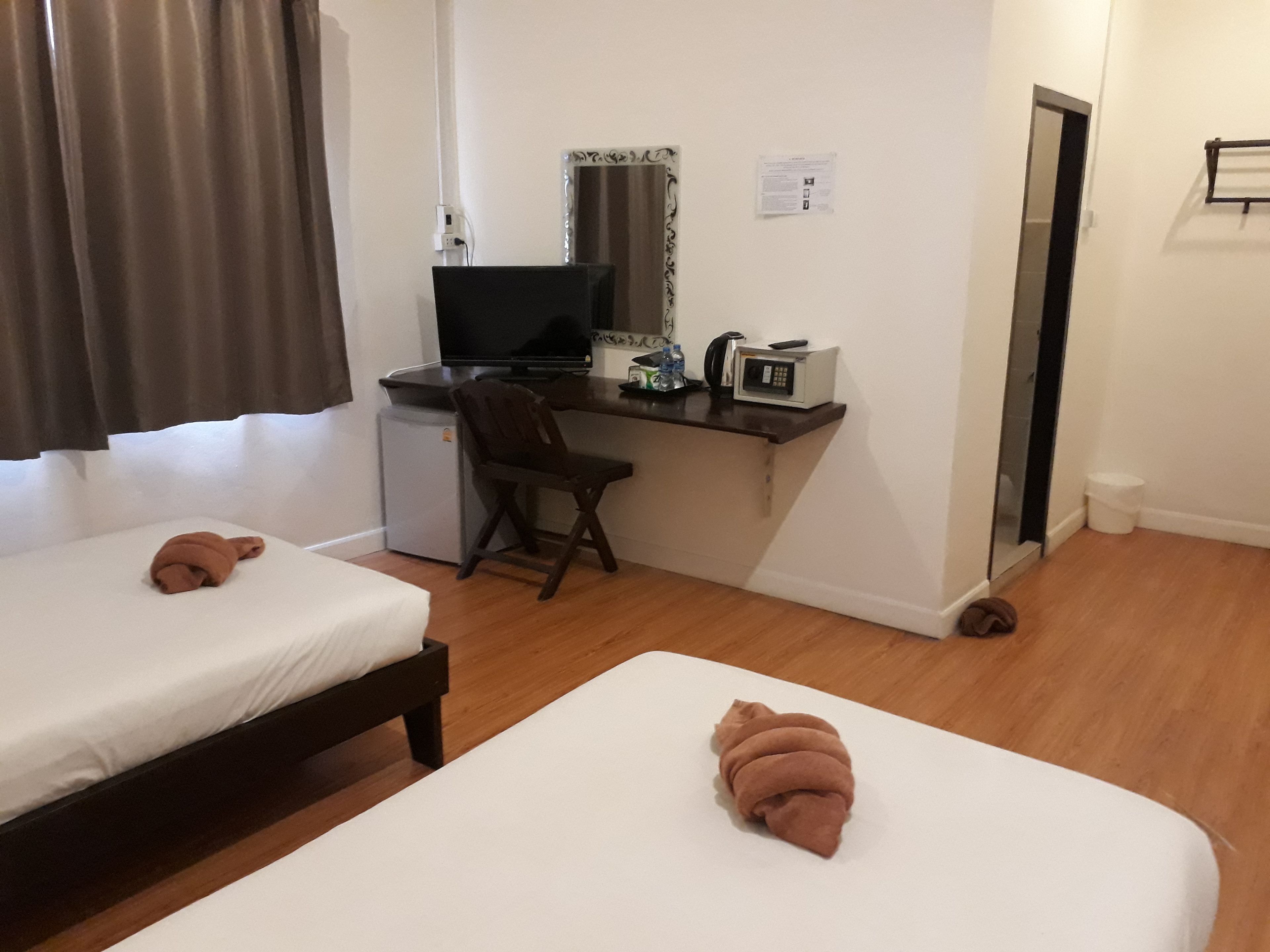Quarto de hotel com duas camas, uma escrivaninha com computador, uma cadeira, micro-ondas e um pequeno frigorífico.