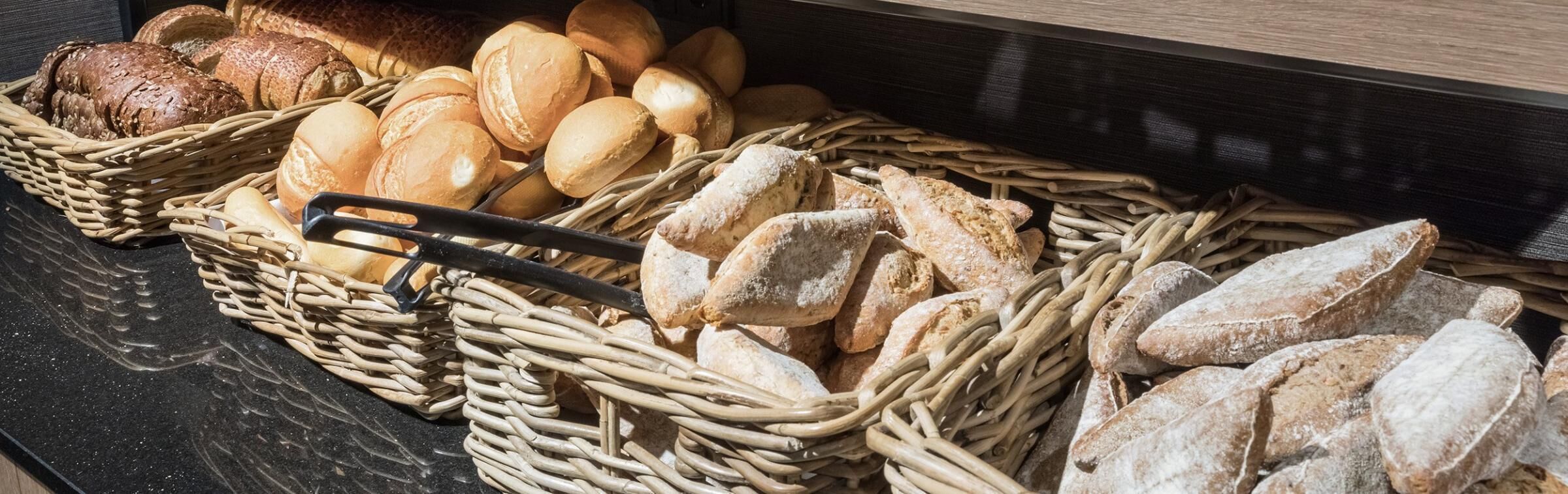 Diversos tipos de pão expostos em cestos de vime.