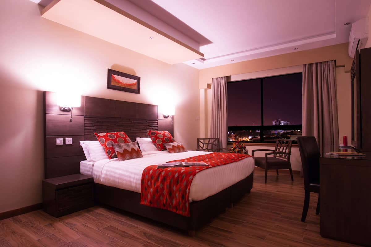 Quarto de hotel moderno com uma cama grande, uma mesa e uma cadeira.