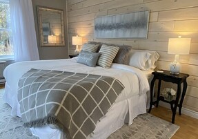 Quarto com uma cama grande, duas mesas de cabeceira com abajures, um espelho e um quadro na parede.