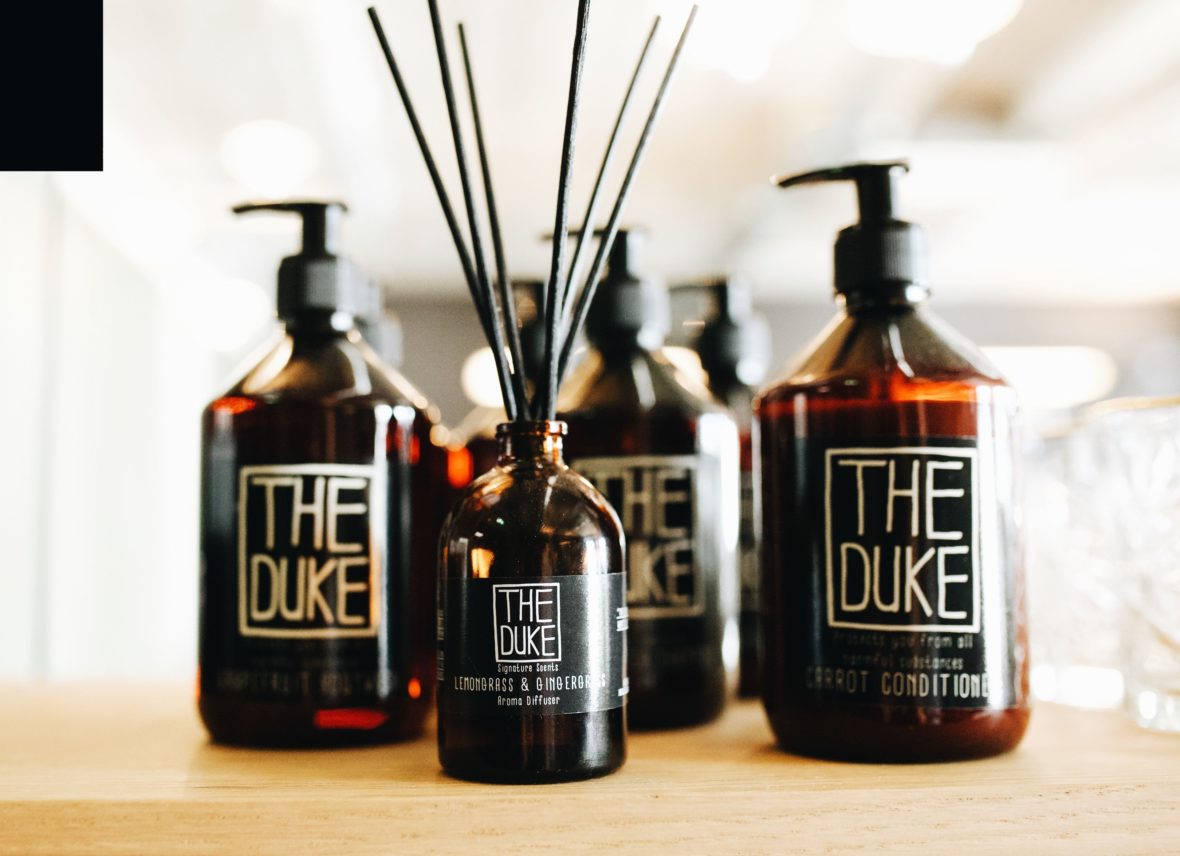 Quatro frascos de fragrâncias exclusivas 'The Duke' sobre uma superfície de madeira.