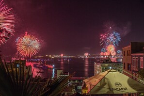 Vista para a orla com fogos de artifício, um guarda-sol Bacardi e uma roda gigante ao fundo.