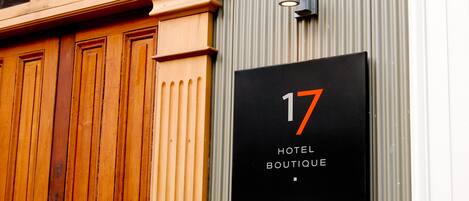 Placa de hotel com o número 17 e a inscrição 'HOTEL BOUTIQUE' sobre um fundo preto.