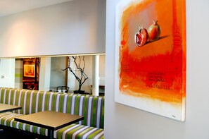 Um restaurante moderno com cabines listradas e uma grande pintura de romãs na parede.