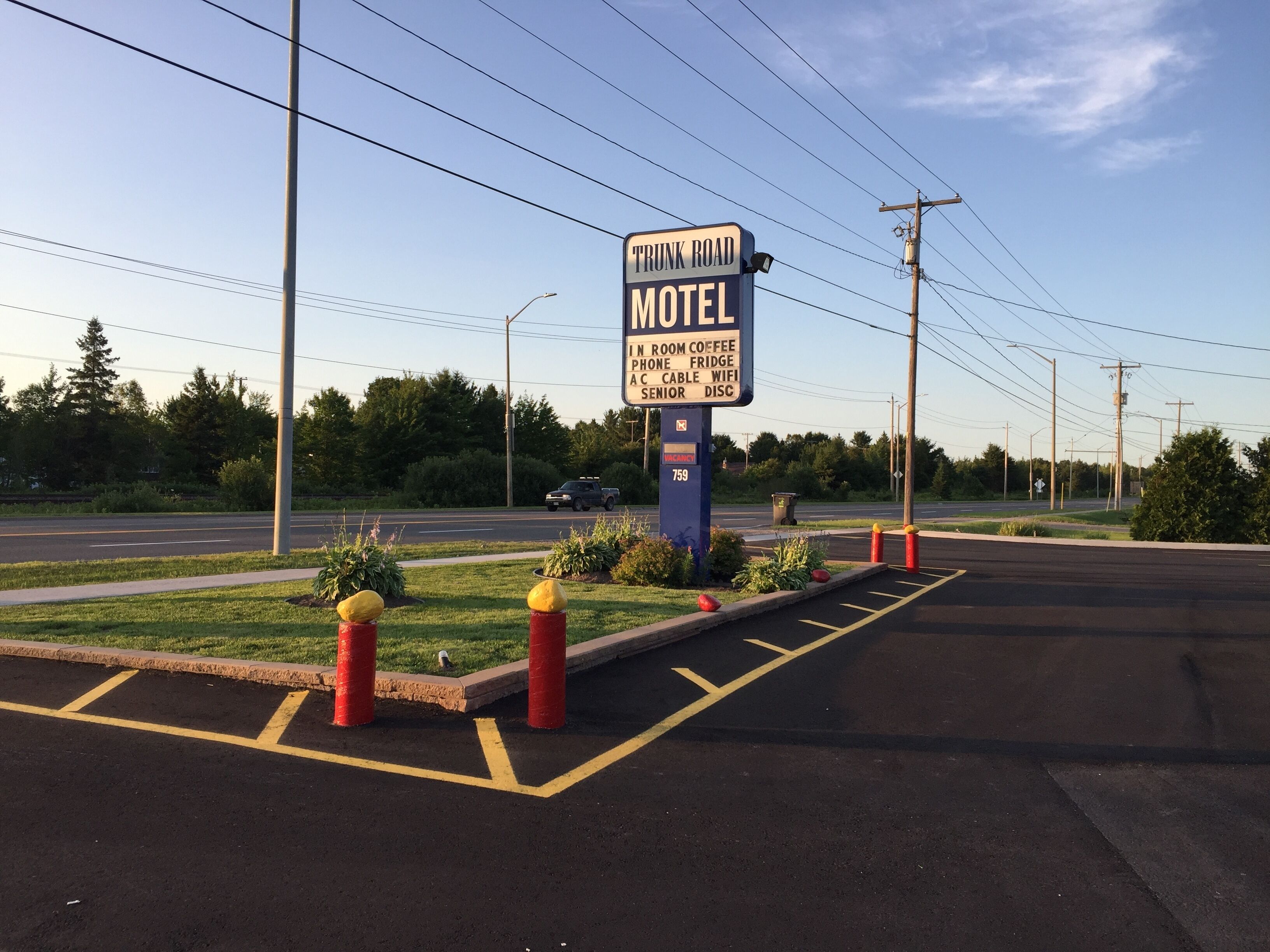 Placa de motel com comodidades como café na suíte, telefone, geladeira, ar condicionado, TV a cabo, wifi, desconto para idosos e número de quarto disponível.