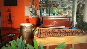 A room with a wooden instrument display, a large drum, and a bed with a sign reading "Hotel San Jerónimo".
