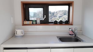 Uma cozinha com janela, chaleira, pia e chá da tarde.