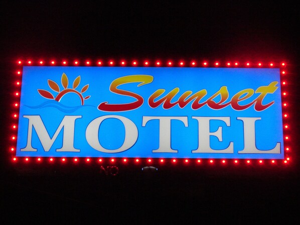 Placa de neon do Sunset Motel com um sol estilizado e palmeira.