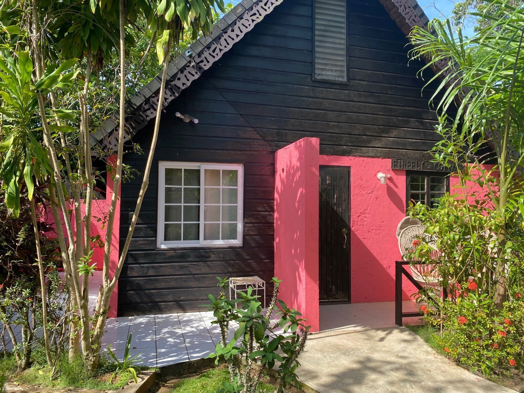 Uma casa com fachada vermelha e preta, uma janela branca e uma porta.