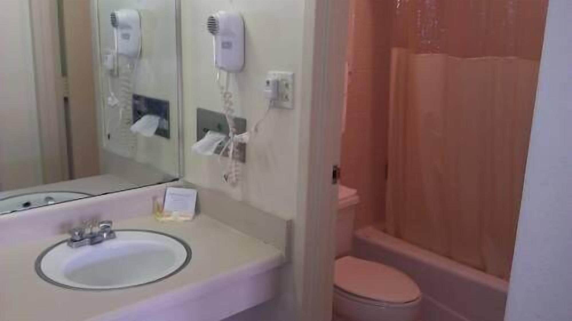 Casa de banho com lavatório, espelho, secador de cabelo e sanita.