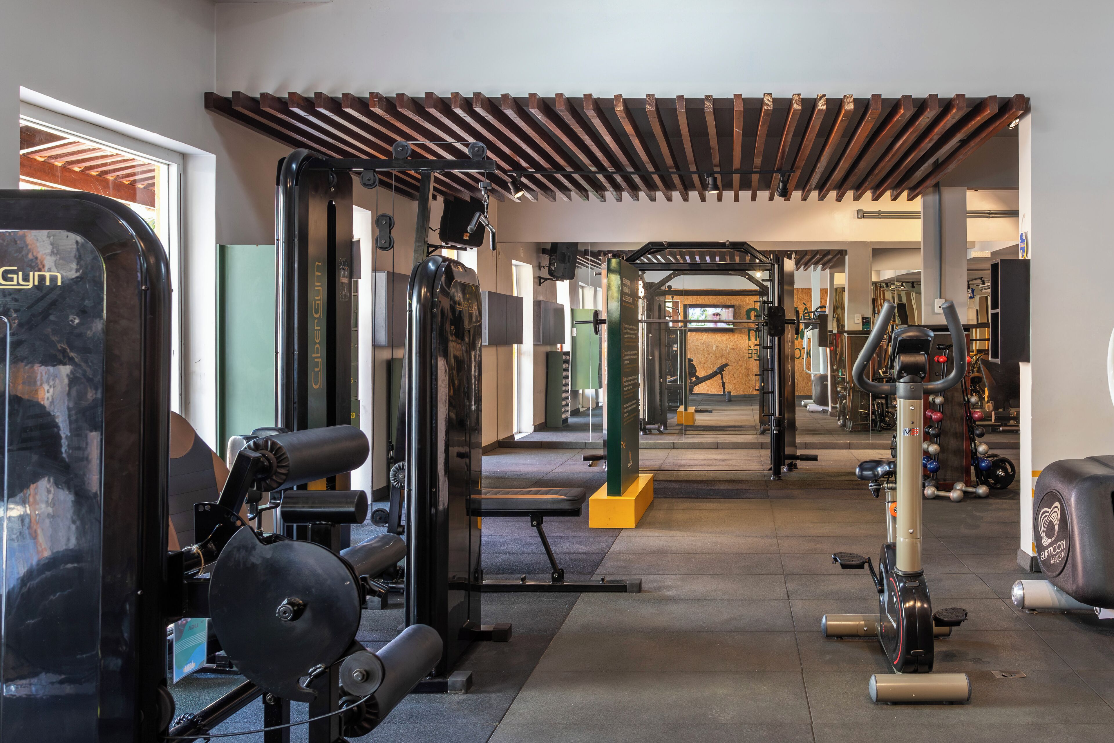Academia com diversos equipamentos de exercícios, incluindo esteira, bicicleta ergométrica e aparelhos de musculação.