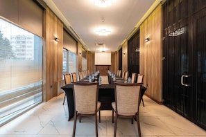 Uma sala de conferências com uma mesa comprida, cadeiras e uma tela de projeção.