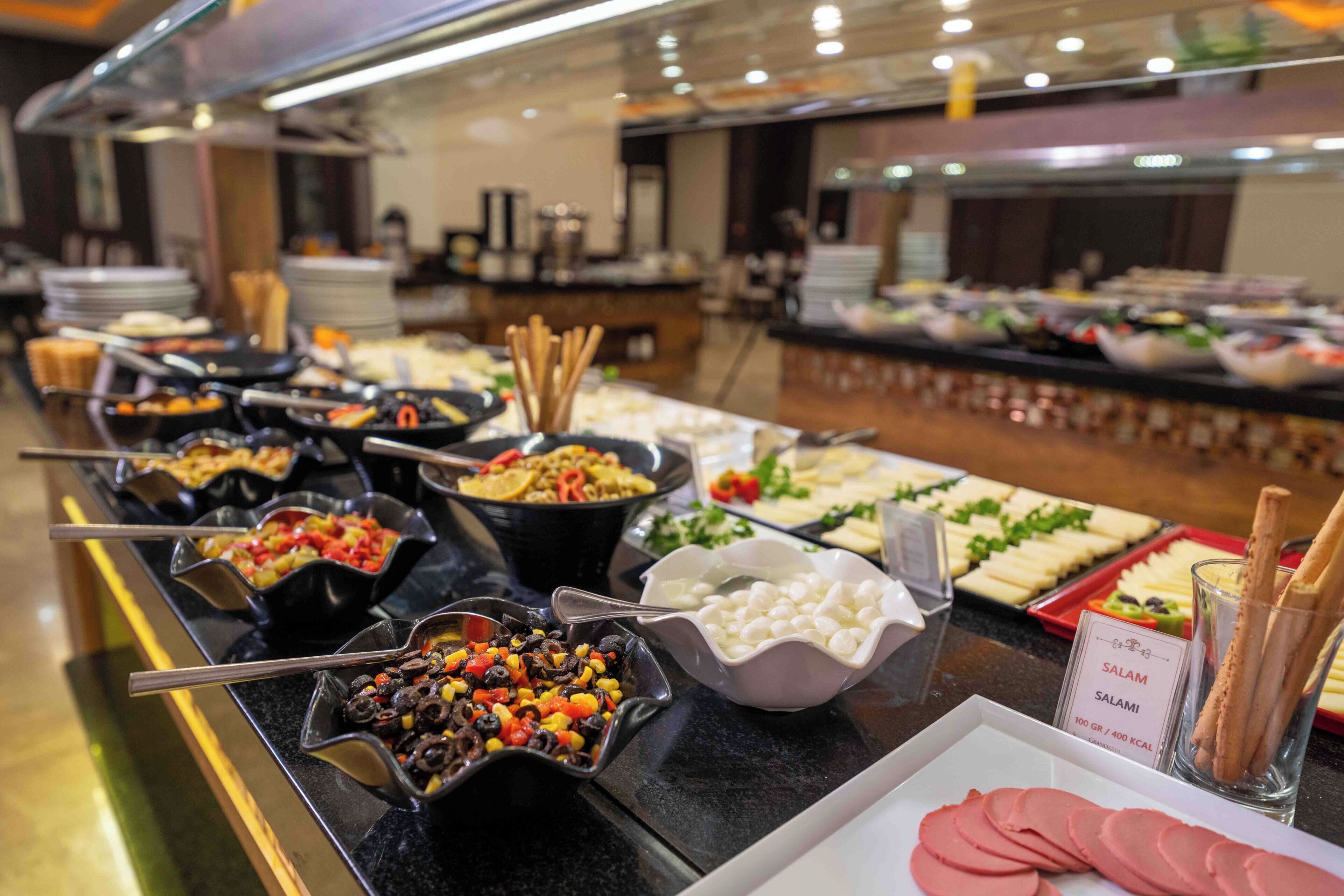 Buffet com diversas opções de comida, incluindo saladas, carnes e patês.