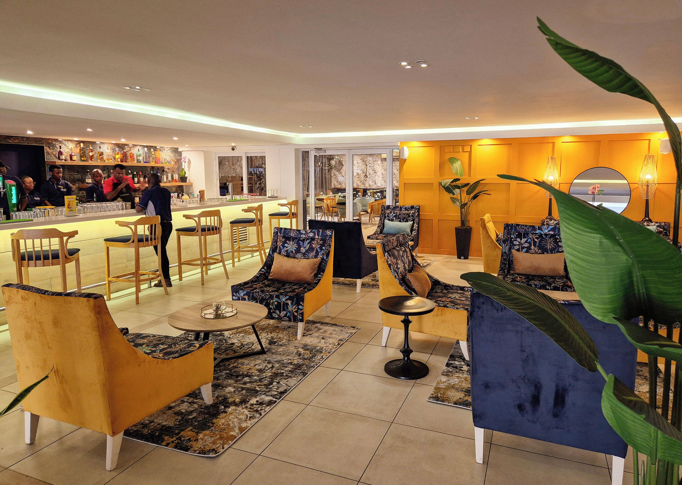 Um saguão de hotel com área de bar, assentos e uma grande planta.
