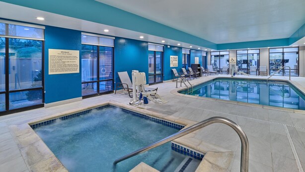 Piscina de hotel com água cristalina, cadeiras de descanso e placas de segurança.