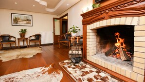 Um quarto com lareira, mobiliário de madeira e um tapete xadrez.