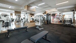 Uma academia com diversos equipamentos de exercício, bancos e uma área para musculação.