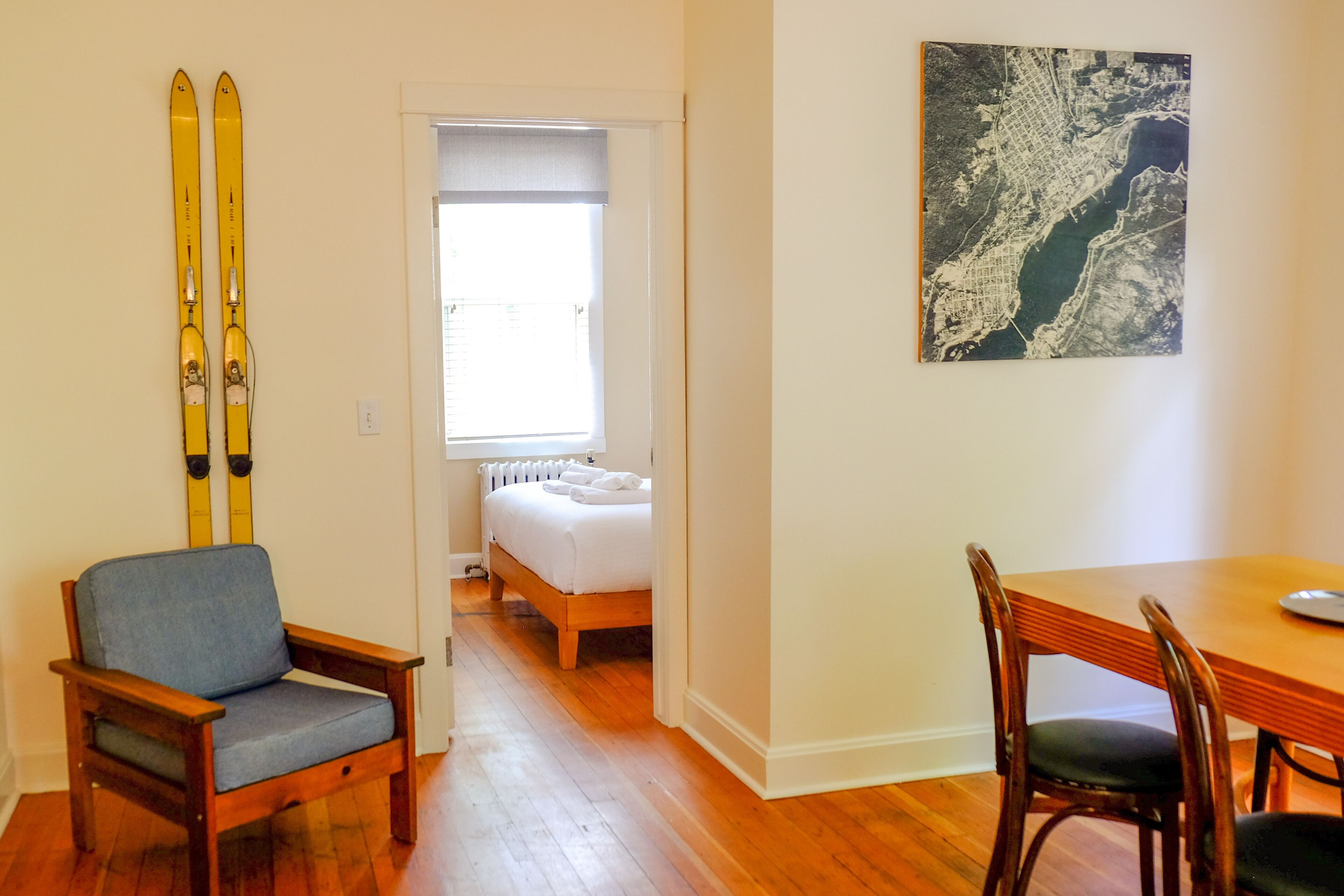 Quarto com cama, cadeira, mesa e um quadro.