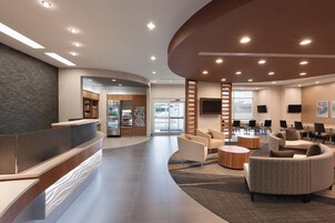 Um lobby moderno com um balcão de recepção curvo, área de estar e vista para a entrada.