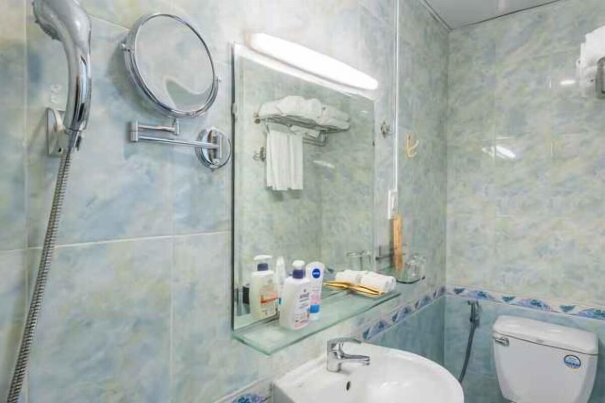 Casa de banho com lavatório, espelho e sanita.