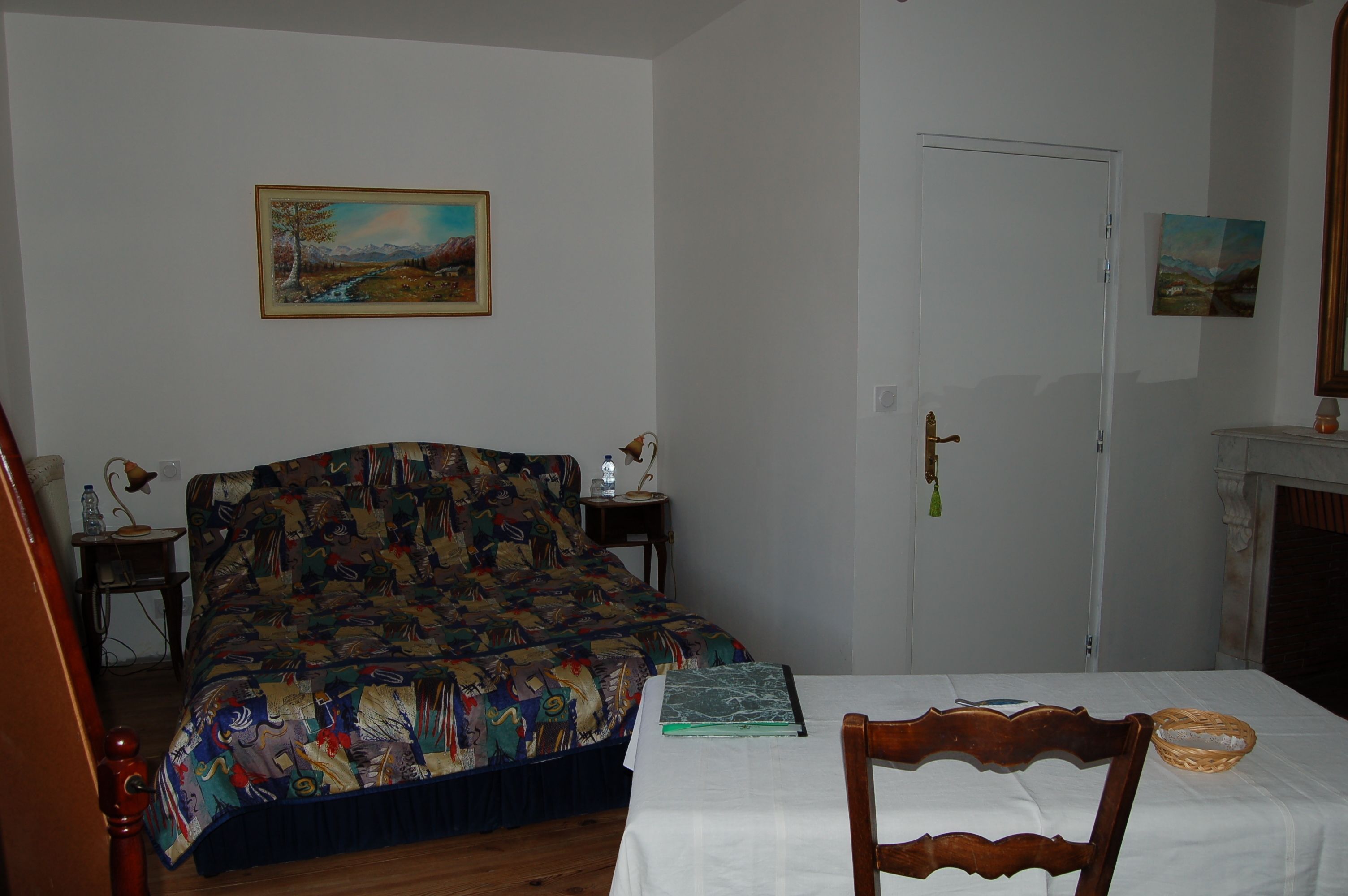 Um quarto com uma cama, uma mesa de cabeceira com abajur, uma cadeira e um quadro na parede.