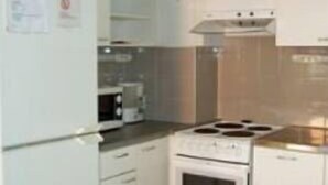 Uma cozinha compacta com armários brancos, micro-ondas embutido, fogão e forno.