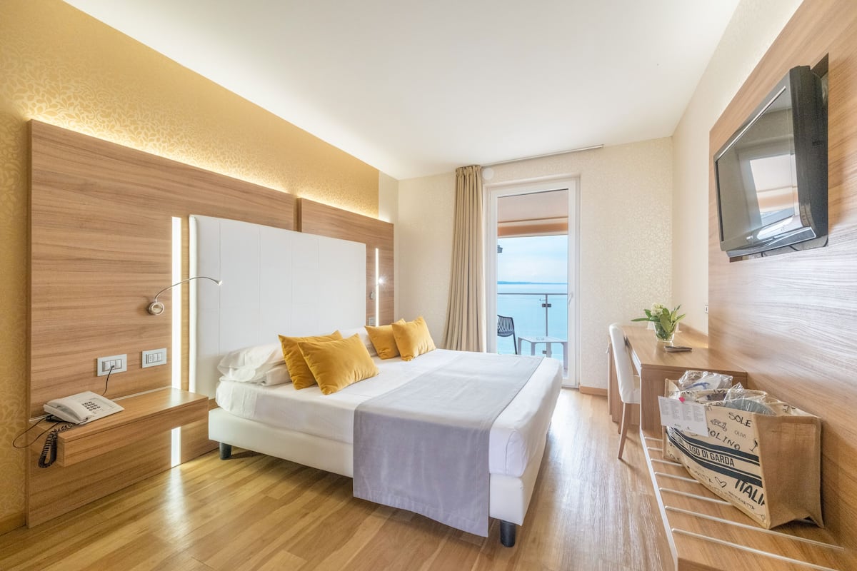 Quarto de hotel moderno com uma cama grande, uma escrivaninha, televisão e varanda com vista.