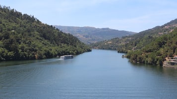 Um rio com um barco, cercado por colinas arborizadas.