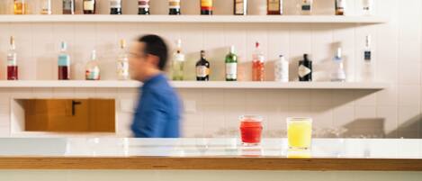 Uma área de bar com prateleiras de garrafas e dois copos de bebidas no balcão.