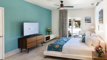 Quarto moderno com cama, televisão, ventoinha no teto e vista para o exterior.