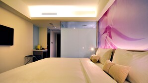 Quarto de hotel com uma cama grande, uma escrivaninha e um espelho.