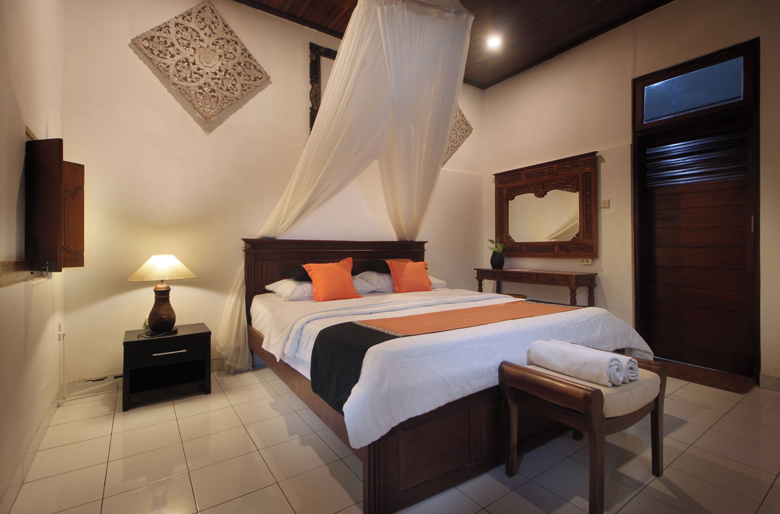 Quarto com cama, mesa de cabeceira, luminária e uma cadeira.