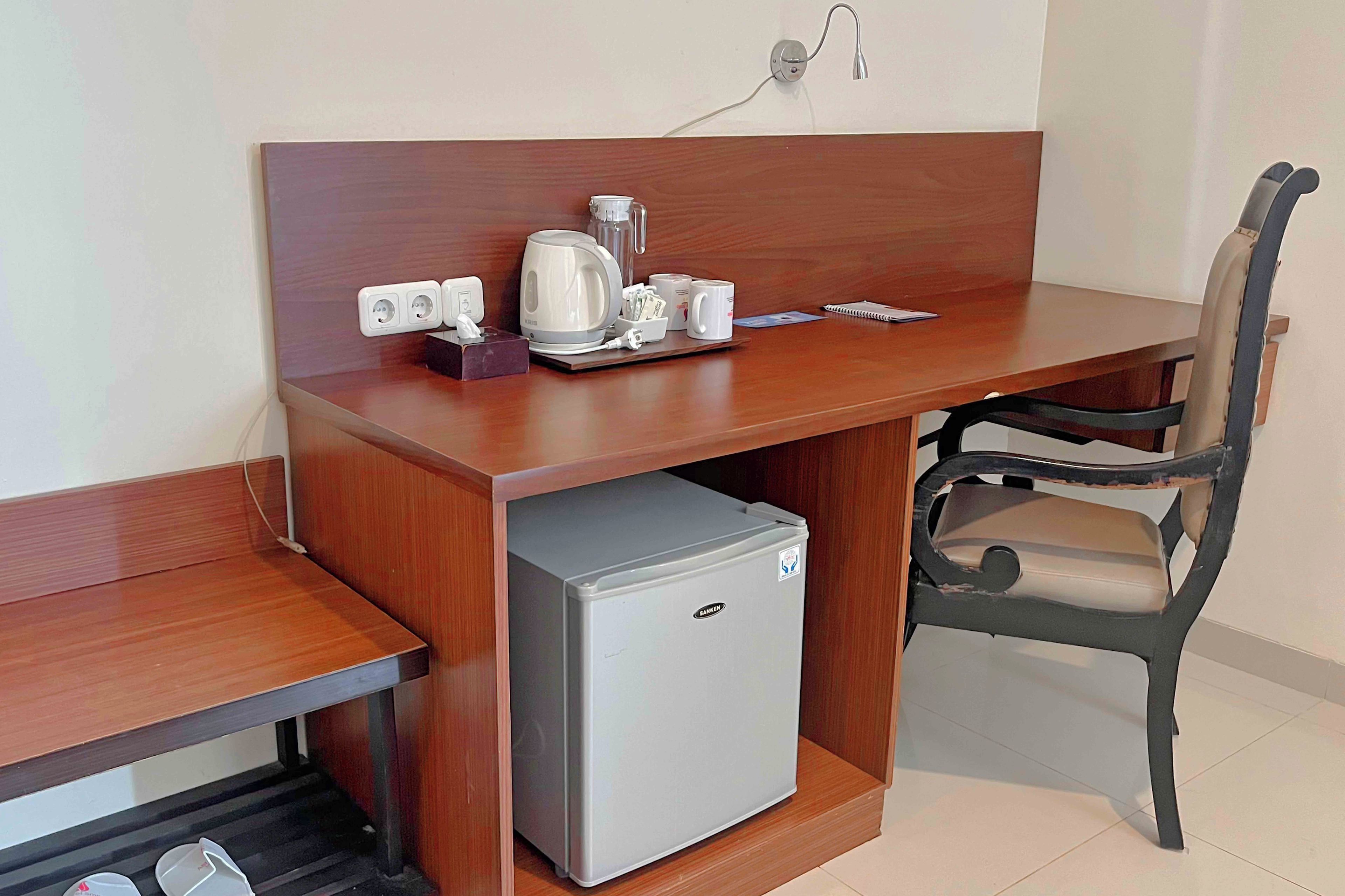Espaço de trabalho compacto com escrivaninha, cadeira e mini-geladeira.