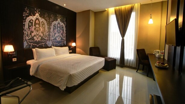 Quarto de hotel moderno com uma cama grande, uma escrivaninha, uma cadeira e uma televisão.