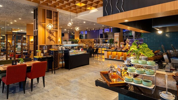 Um restaurante moderno com teto alto, painéis de madeira e diversas opções de assentos, incluindo mesas e cadeiras.