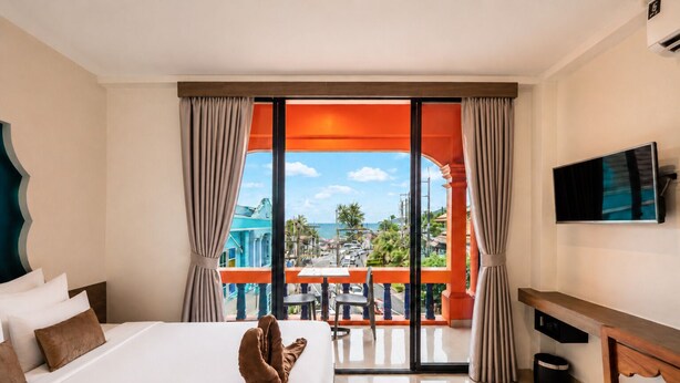Quarto de hotel com cama, televisão, varanda com vista para a cidade e mesa com cadeiras.