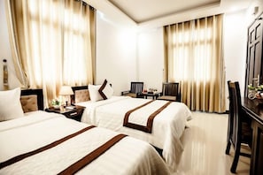 Quarto de hotel com duas camas, uma escrivaninha e uma cadeira.