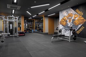 Uma academia moderna com diversos equipamentos de ginástica, um mural na parede e interior limpo e bem iluminado.