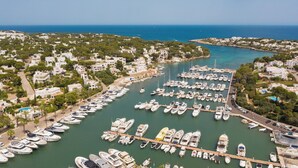 Uma marina com vários barcos atracados, cercada por edifícios residenciais e vegetação.