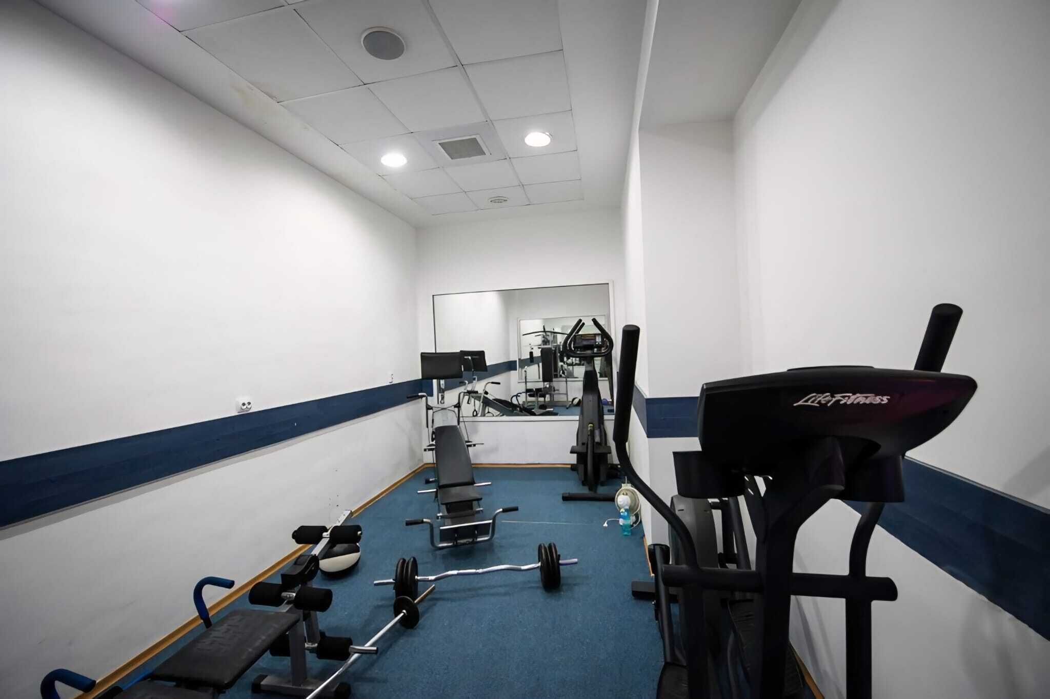 Academia com equipamentos de cardio, máquinas de peso e pesos livres.