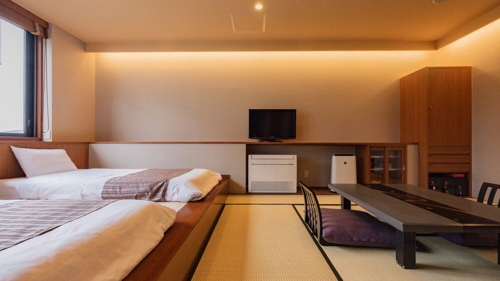 Quarto de hotel com duas camas, televisão, escrivaninha e guarda-roupa.